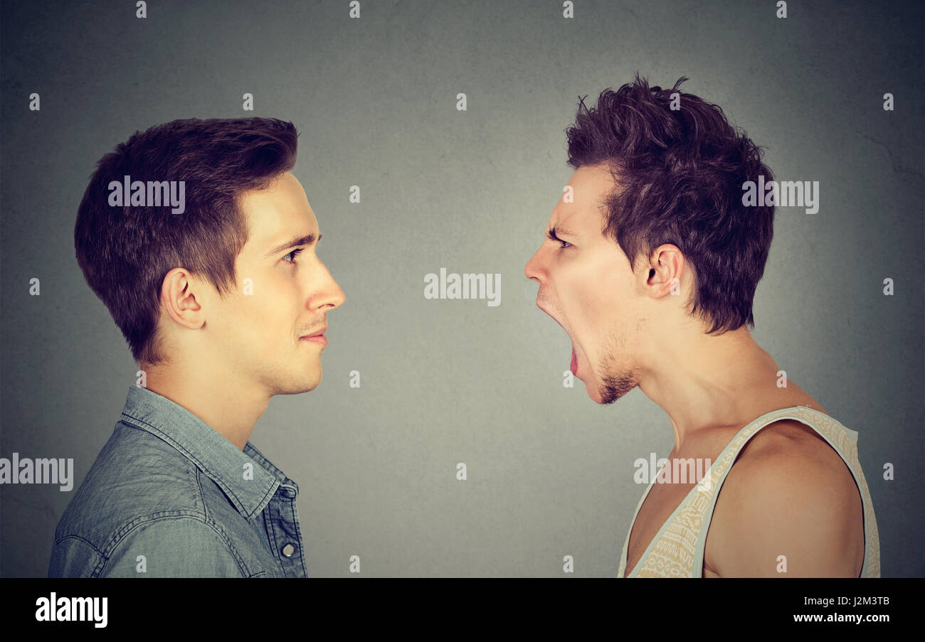Side profile portrait of young angry man screaming at a calm smiling guy Stock Photo - Alamy