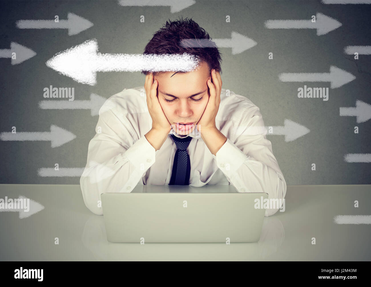 Uncertain confused bored young man sitting in front of laptop computer ...