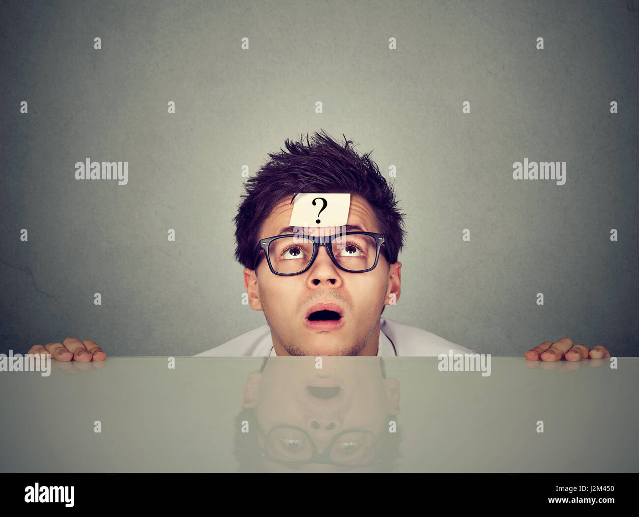 thinking man with question mark peeking from under the table looking up ...