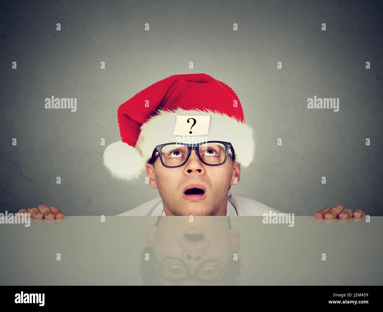 Young man in santa claus hat with question mark Stock Photo - Alamy