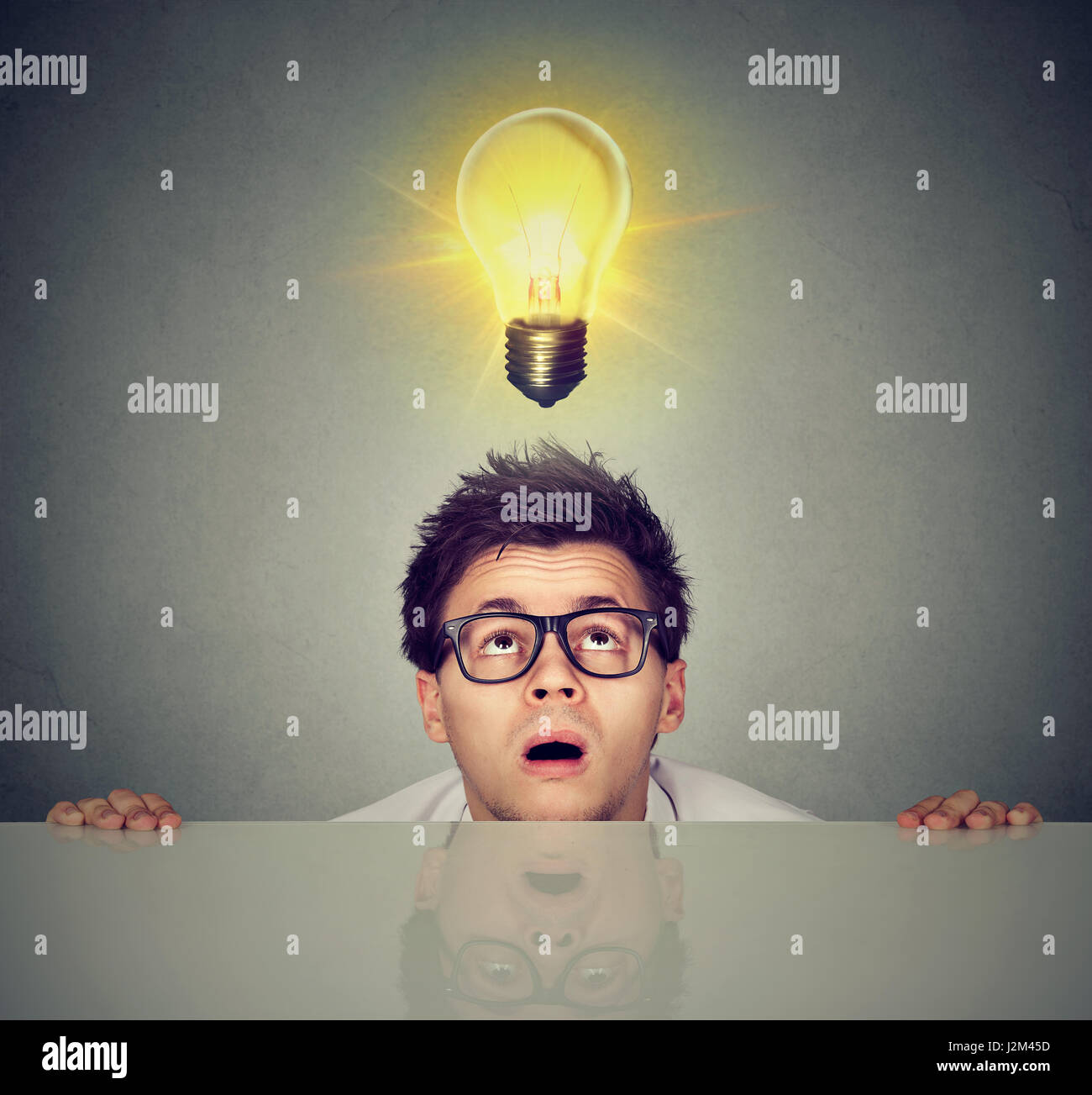 Man coming out from under the table looking up at bright light bulb ...