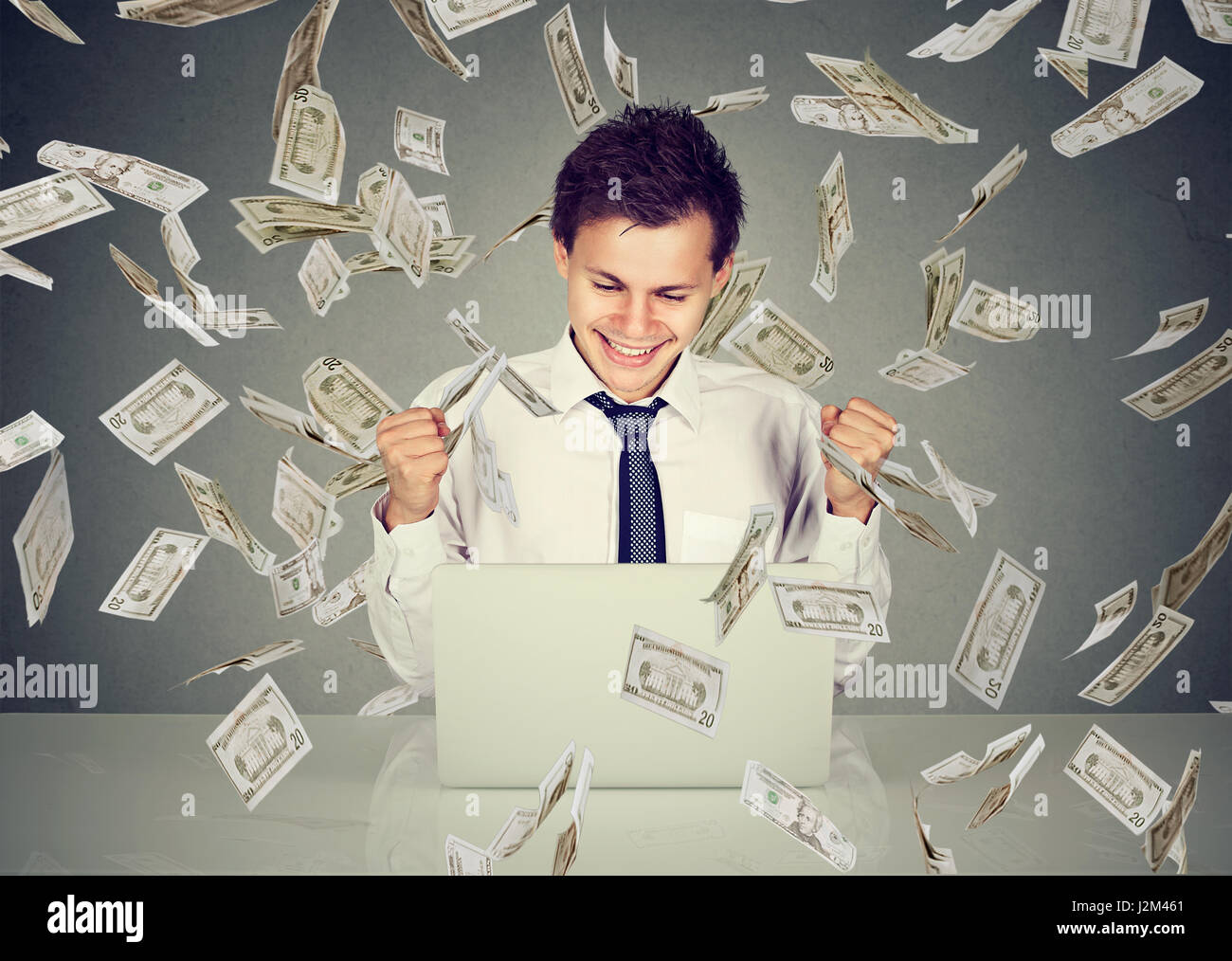 Young man using a laptop building online business making dollar bills ...