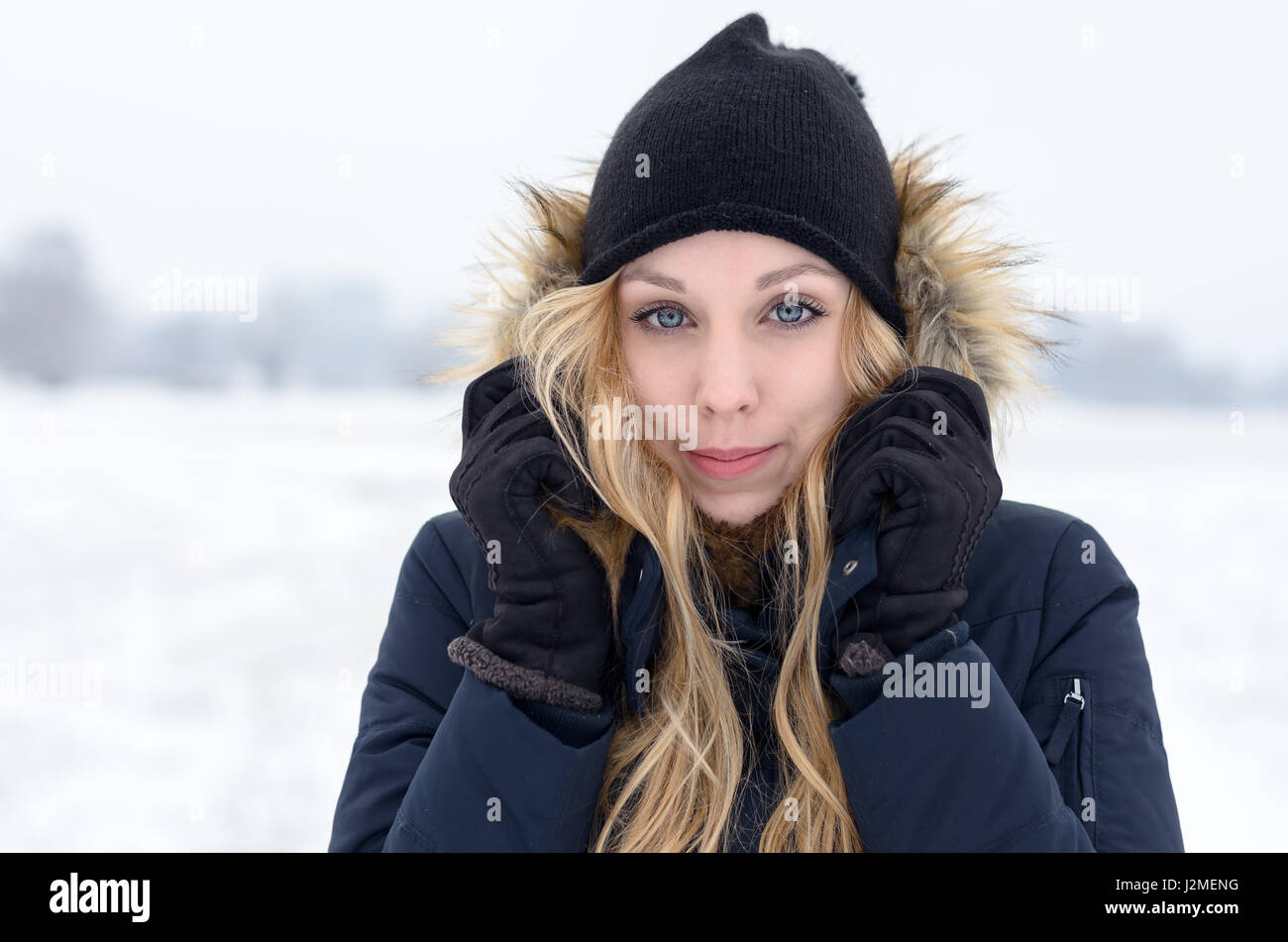 Cold young woman in a freezing winter landscape blanketed in fresh ...