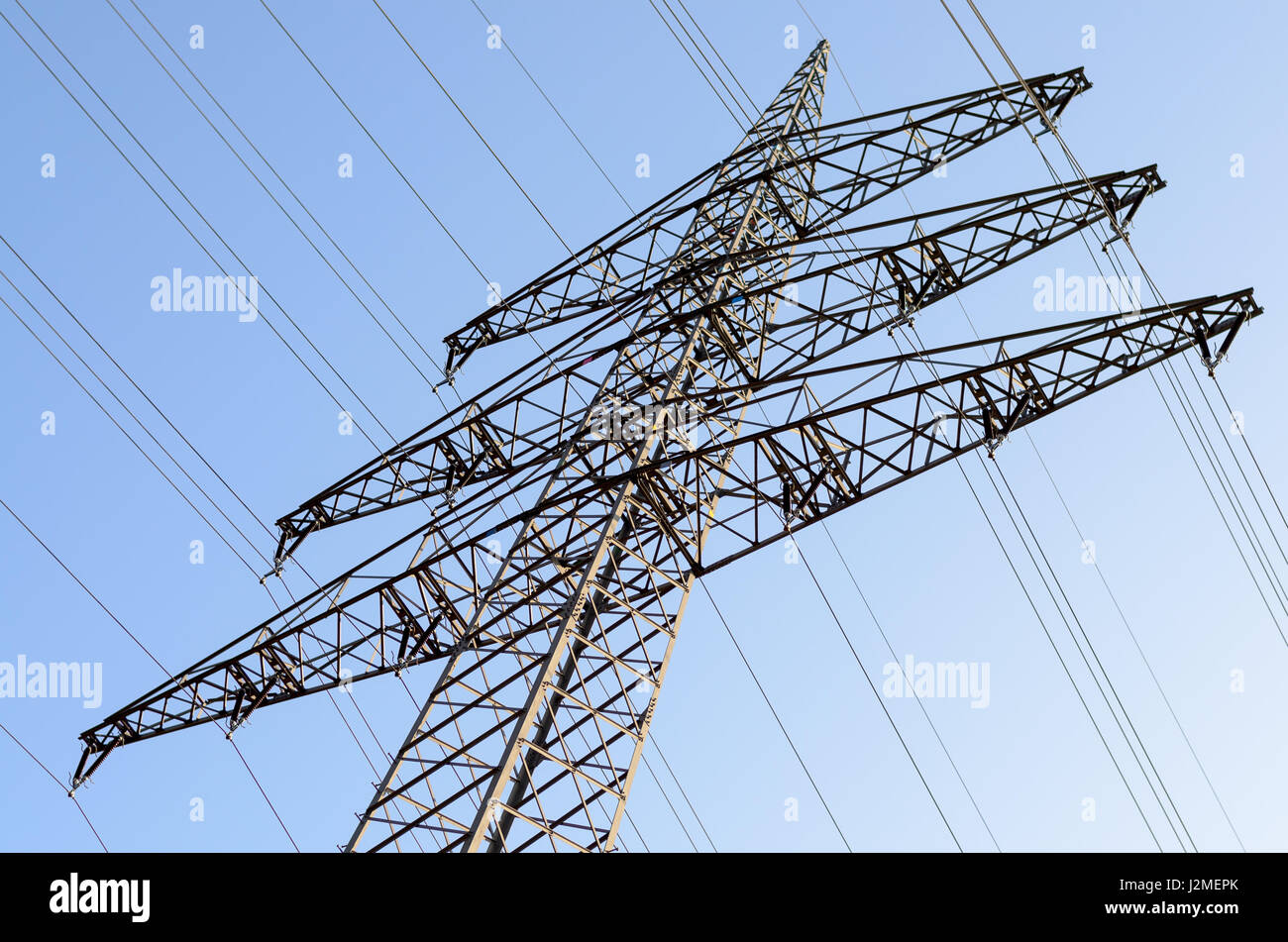 Low angle view on large high tension power lines with clear blue sky in ...