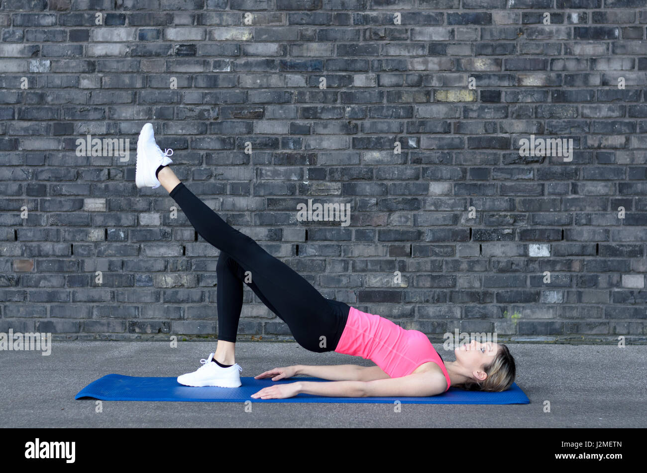 Fit smiling woman looking over shoulder while doing abdominal exercises ...