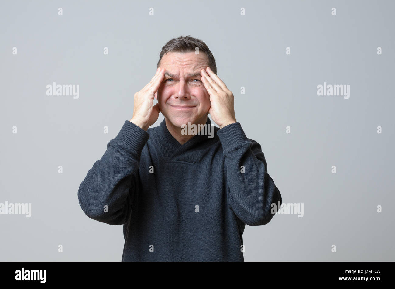 Half body portrait of frustrated man with his hands to his temples ...