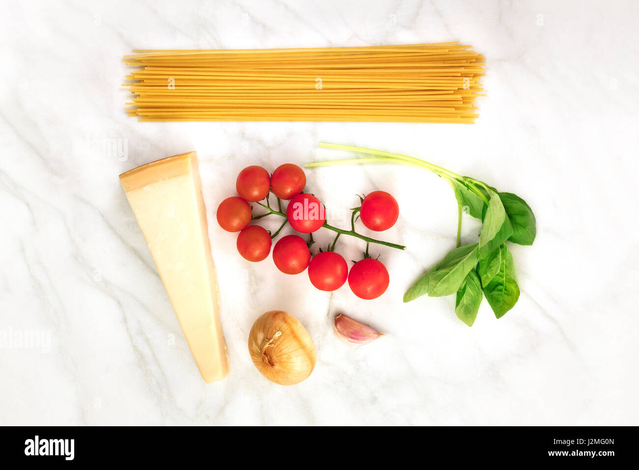 An overhead photo of basic pasta ingredients on a white marble table ...