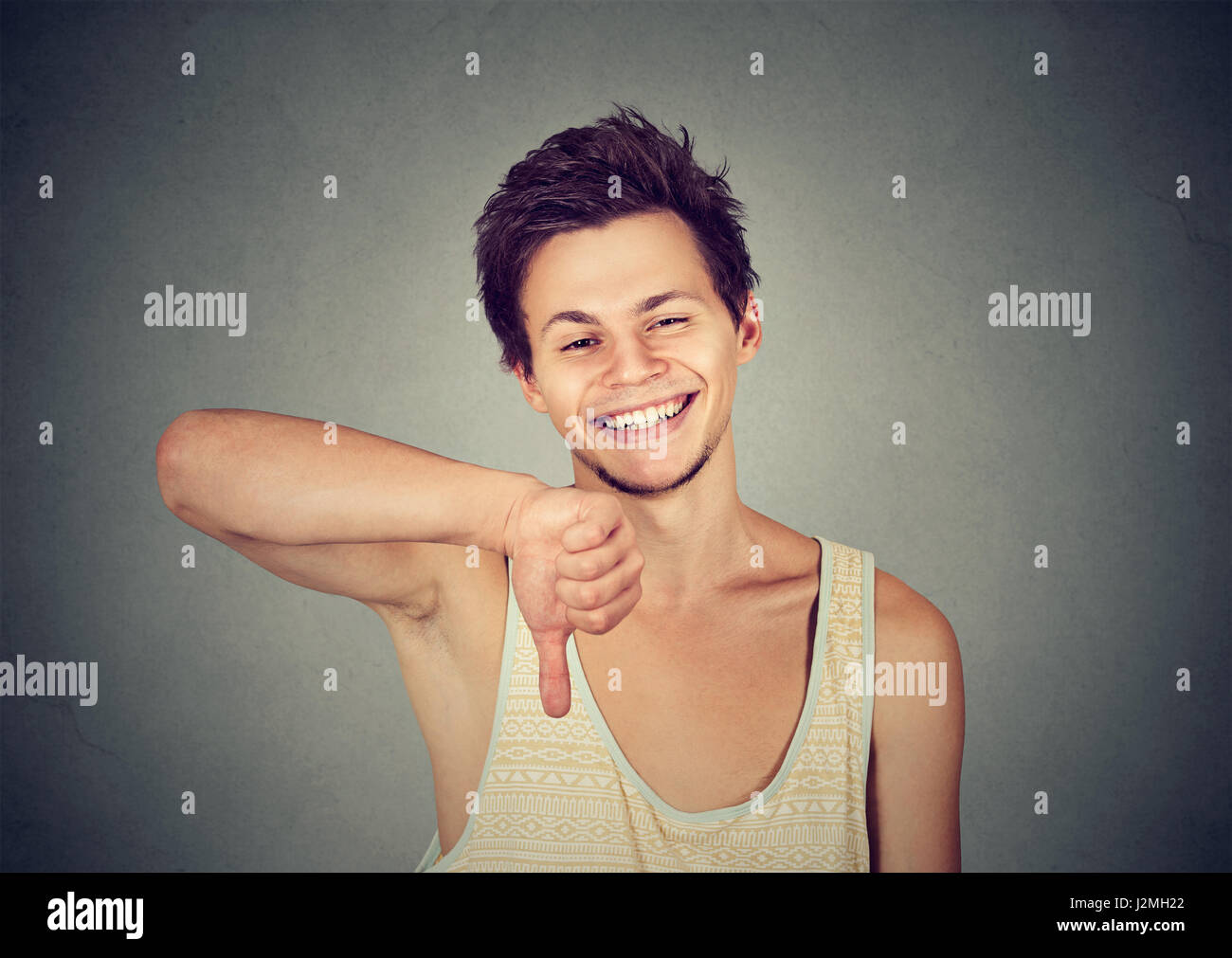 Sarcastic young man showing thumbs down sign hand gesture, happy ...