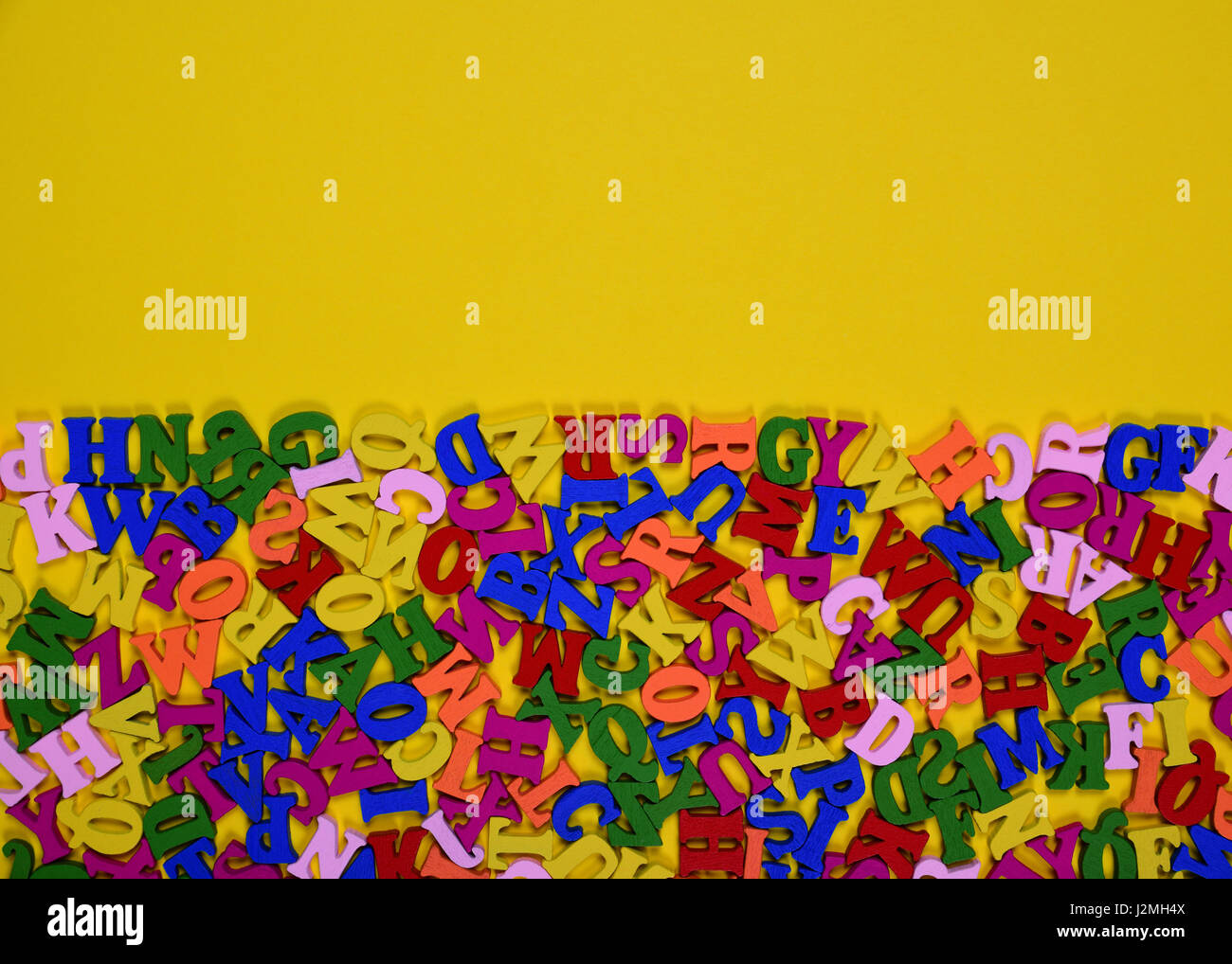 Wooden multicolored letters of the English alphabet on a yellow surface ...