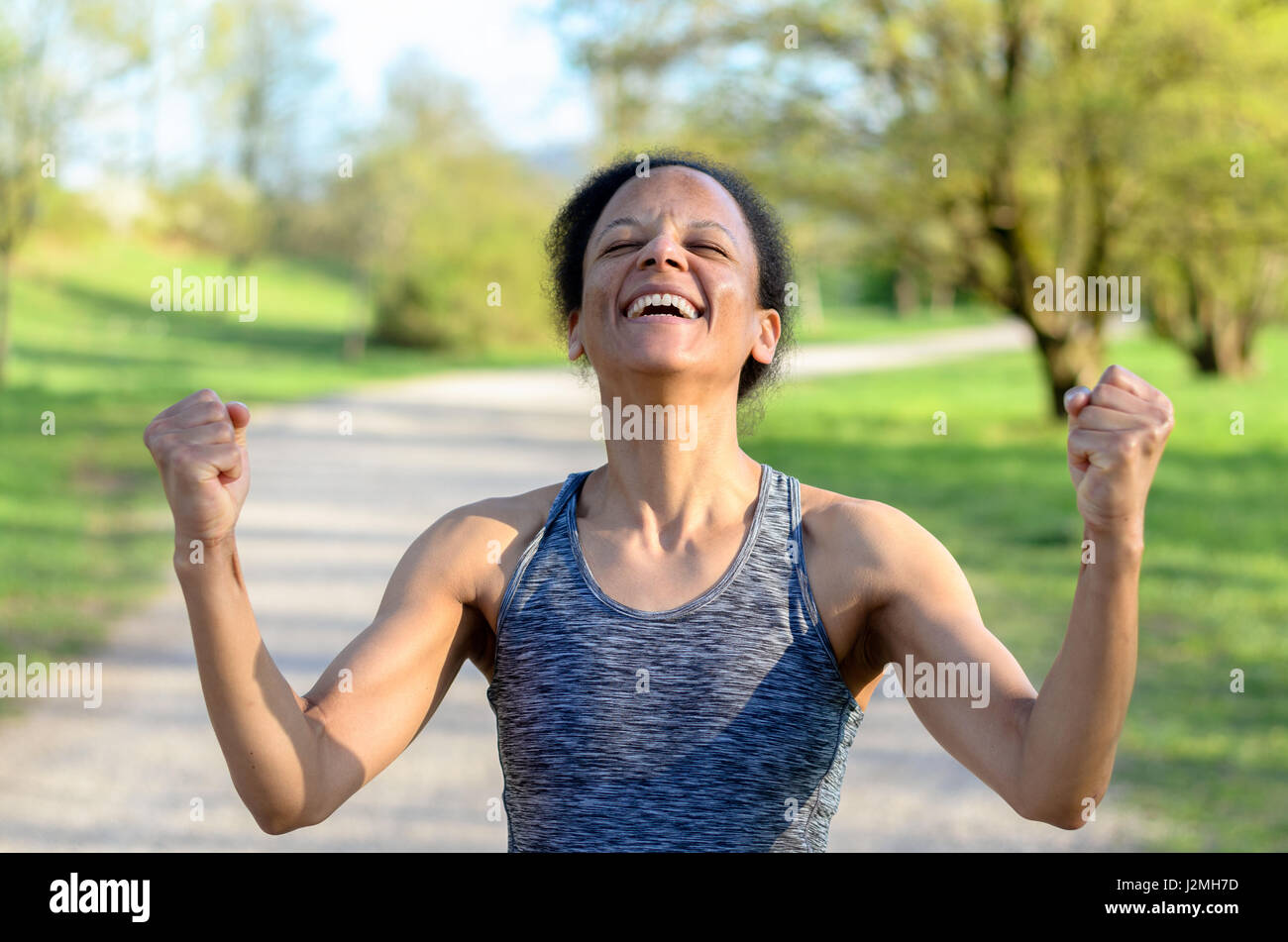 Young african woman cheering and raising her arms after winning a ...
