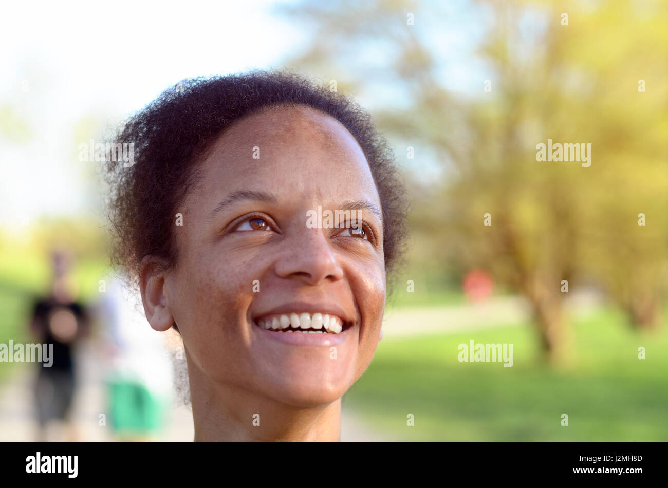 Side View of a Young african woman smiling while she is looking up to ...