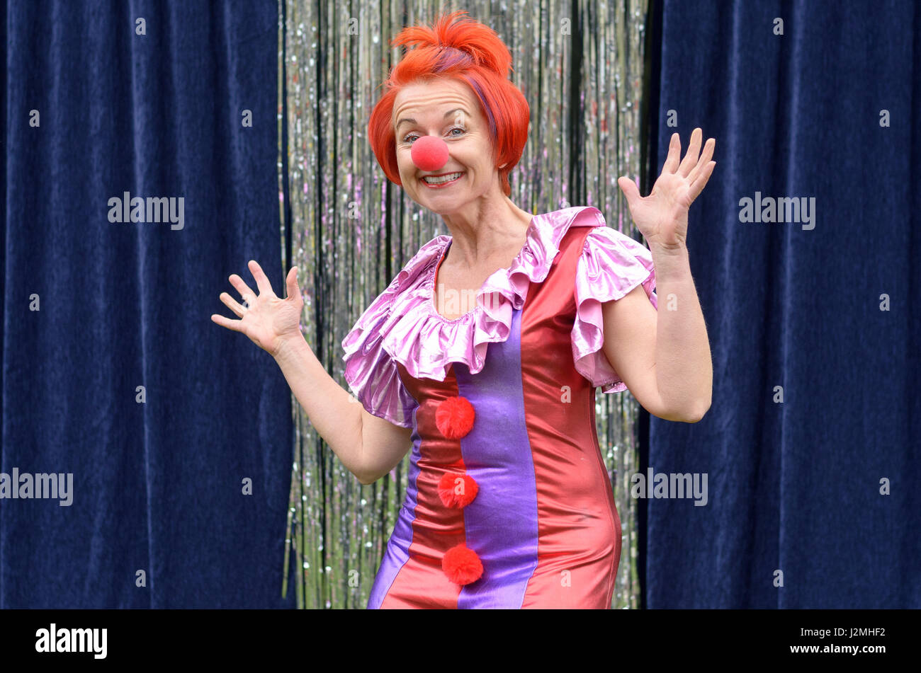 Cute fun redhead performer in a red clowns nose and brightly colored ...
