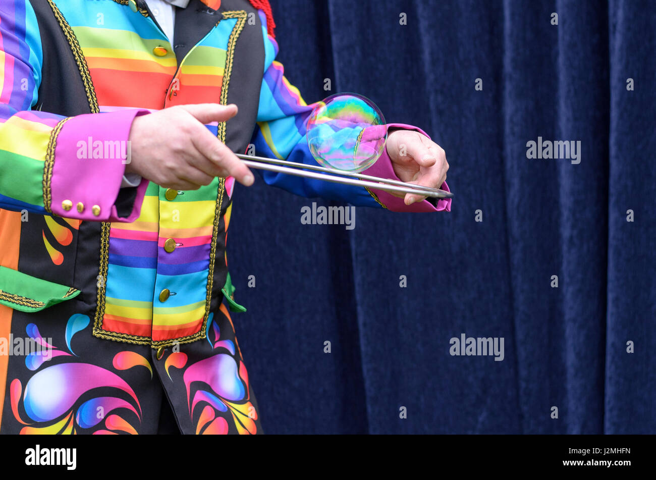 Performer in a bright costume encircling an iridescent sparkling bubble ...