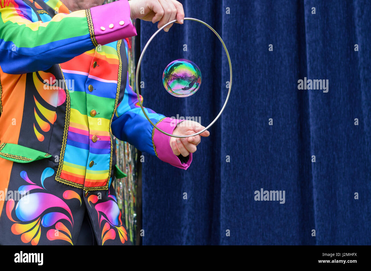 Performer in a bright costume encircling an iridescent sparkling bubble ...