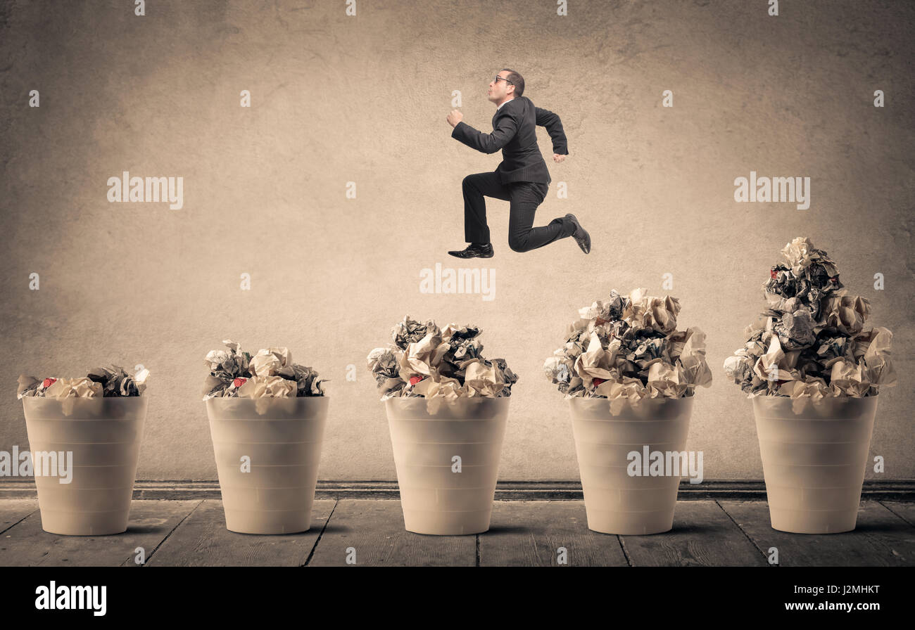 Businessman jumping above trash bins Stock Photo - Alamy