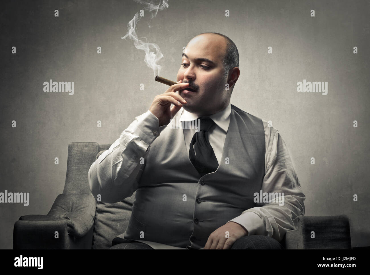 Elegant man smoking cigar inside Stock Photo - Alamy