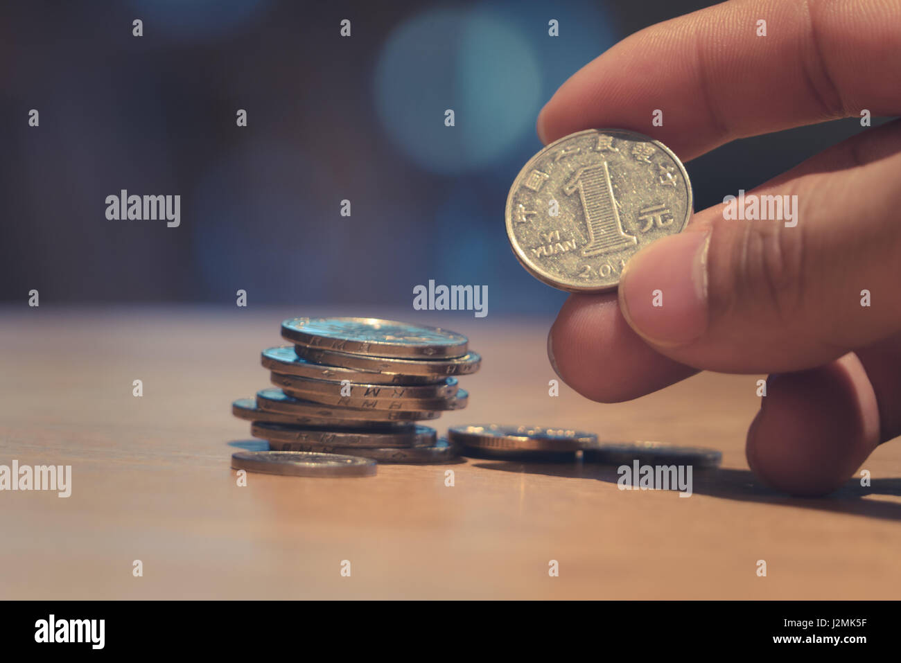 A man finger holding a coin with coin stack on bokeh background and ...