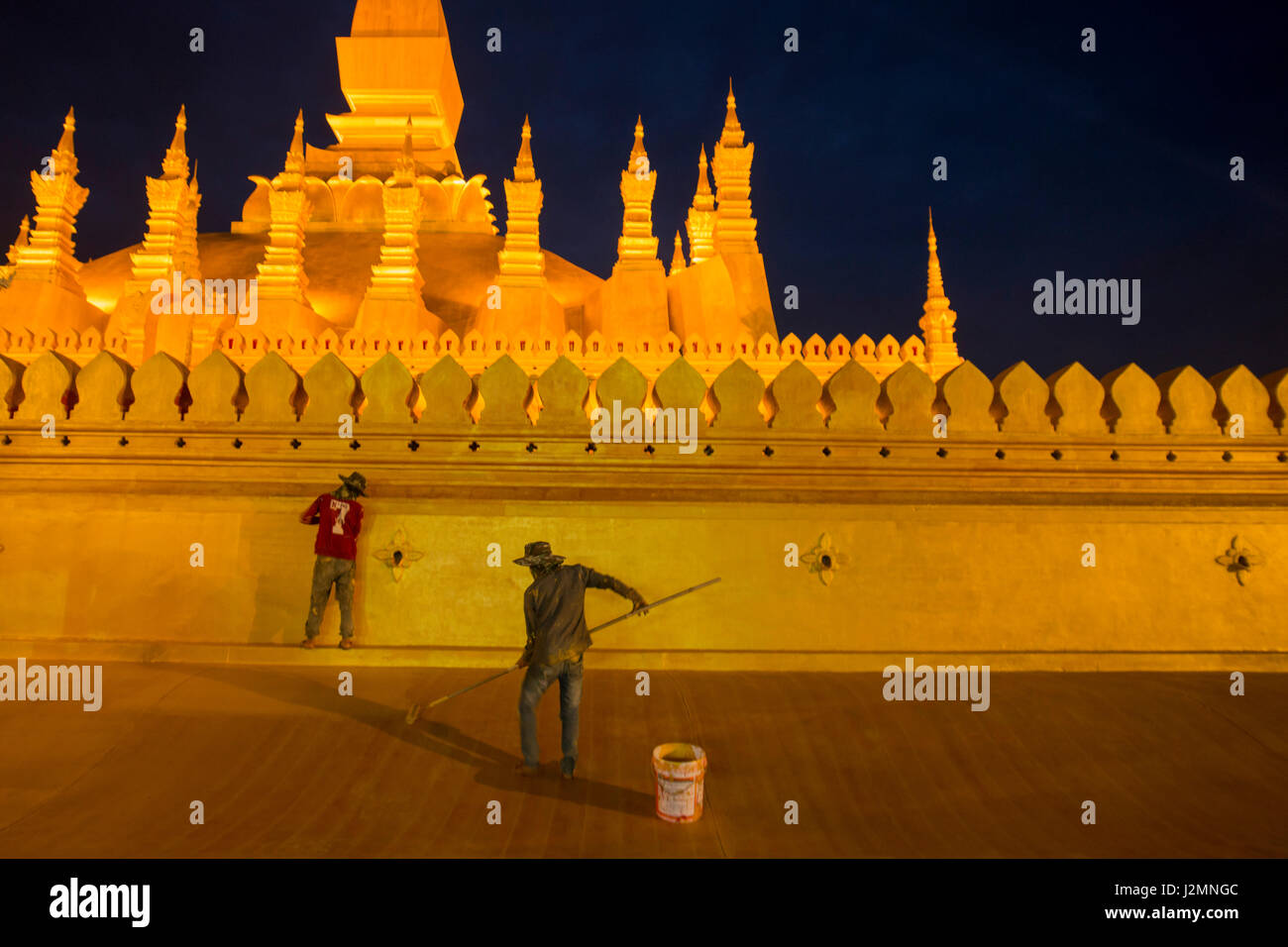 a painter is painting the Stupa with golden colours at the Pha That ...