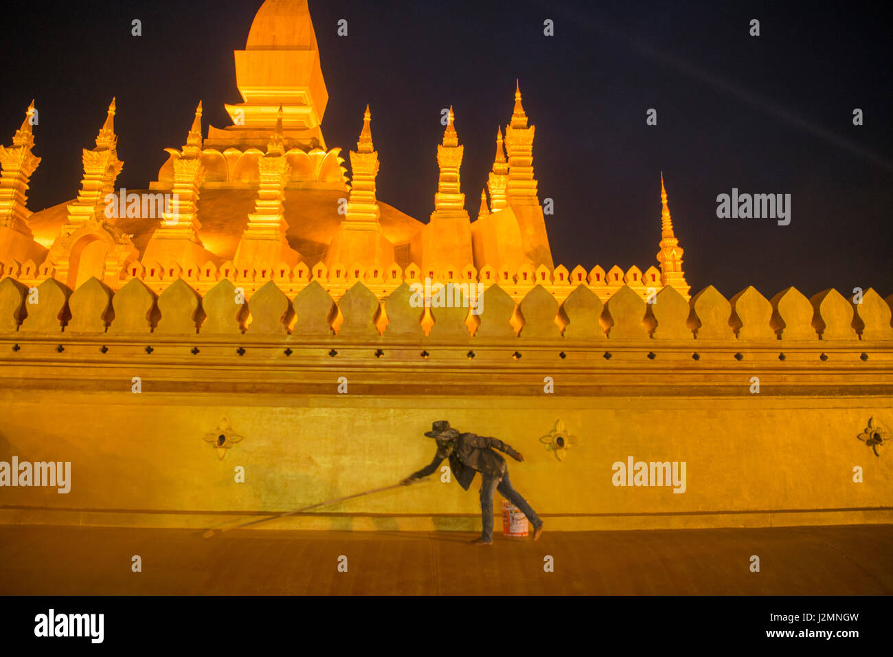 a painter is painting the Stupa with golden colours at the Pha That ...