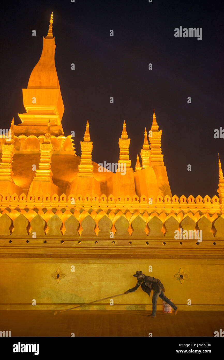 a painter is painting the Stupa with golden colours at the Pha That ...