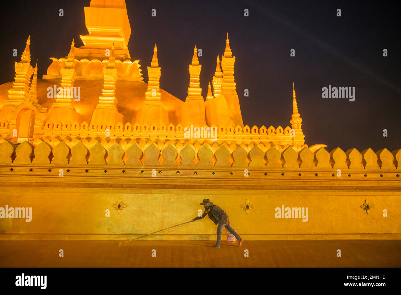 a painter is painting the Stupa with golden colours at the Pha That ...