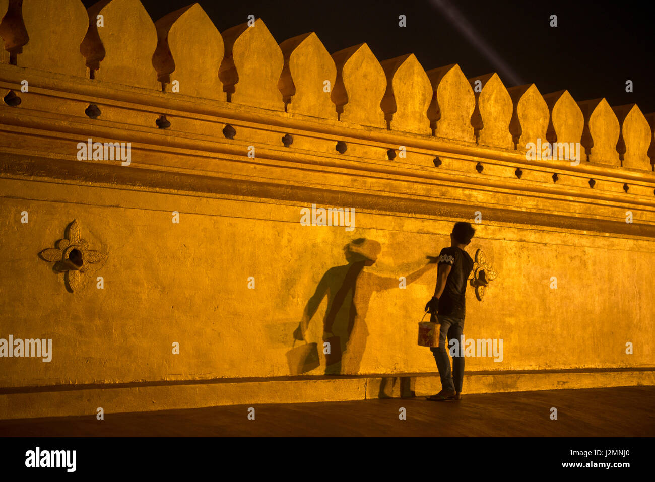 a painter is painting the Stupa with golden colours at the Pha That ...