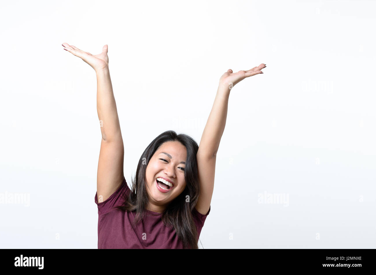 Young woman raising her arms with a pleased smile Stock Photo - Alamy