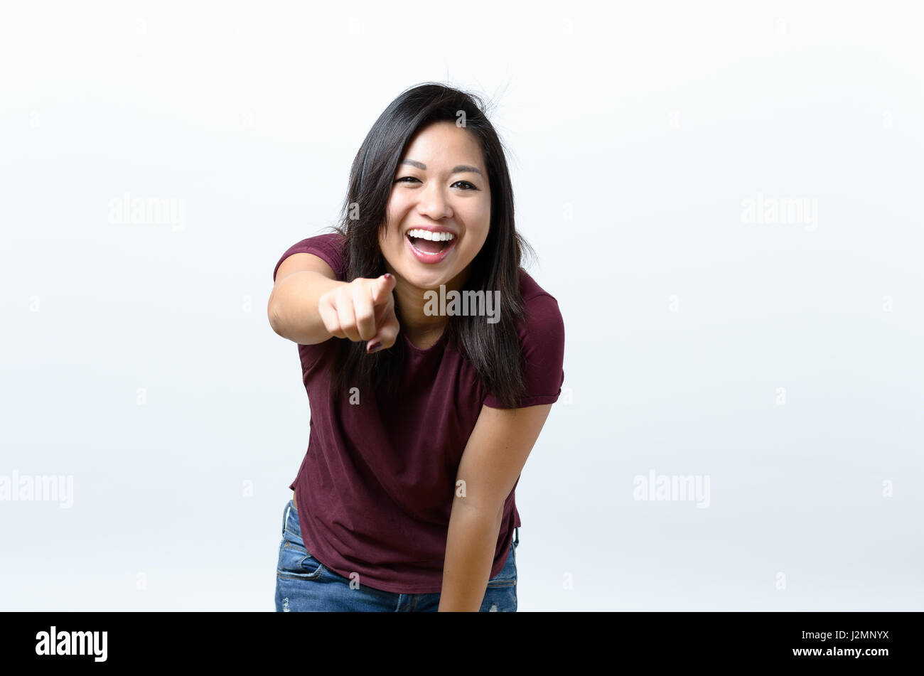Laughing vivacious young Chinese woman pointing at the camera while ...