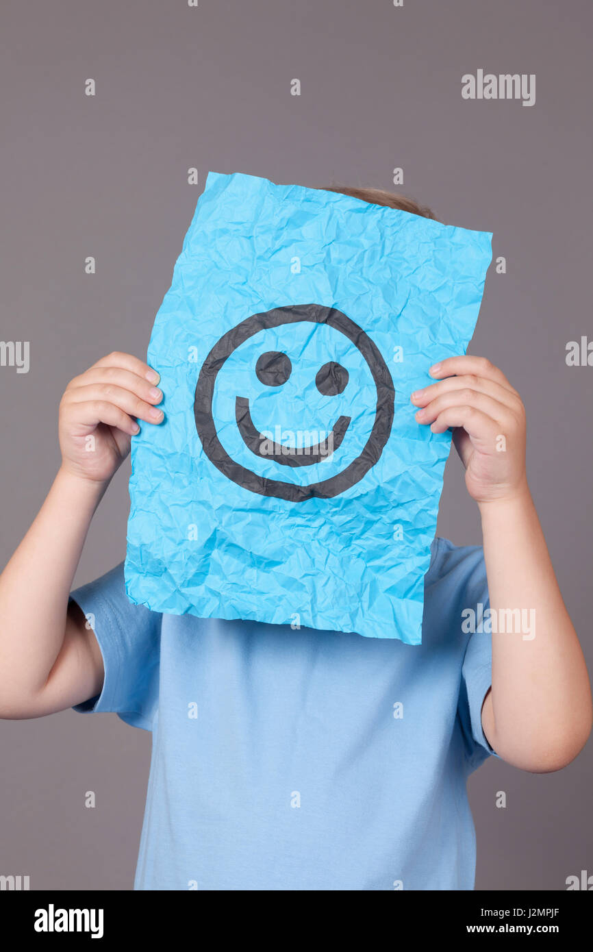 Young boy holding sheet of paper with smiley face. Close up Stock Photo ...