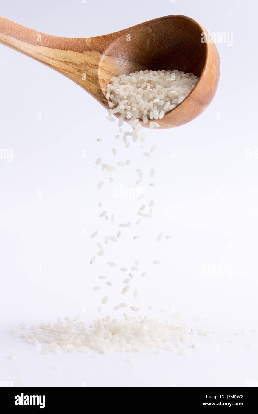 Spoon of rice falling on a white background. Rice falling down from a ...