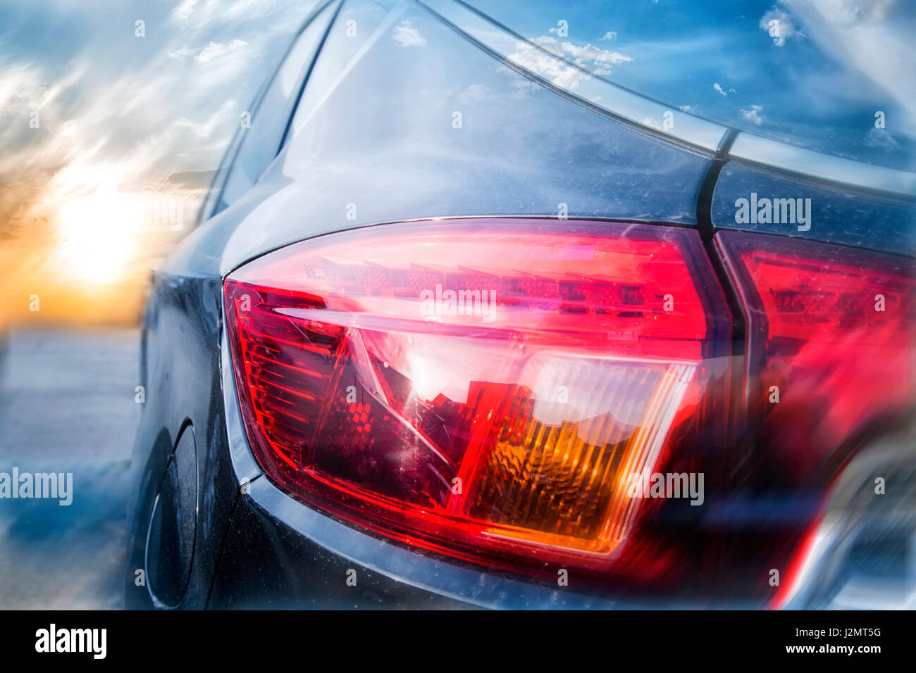 A collage of a back lantern of the car and a rising sun in a background ...