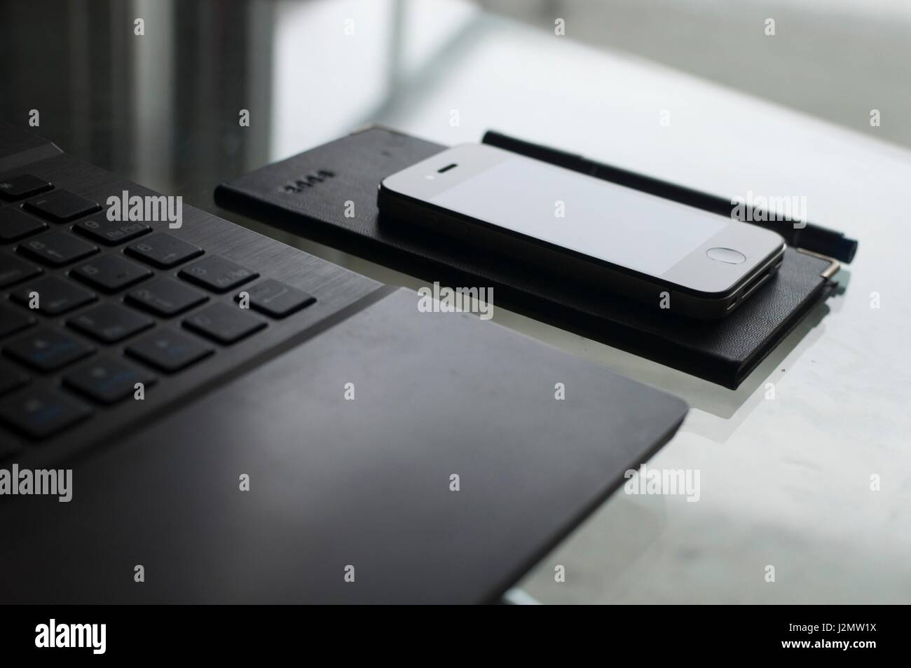laptop with smart phone on glass table Stock Photo - Alamy
