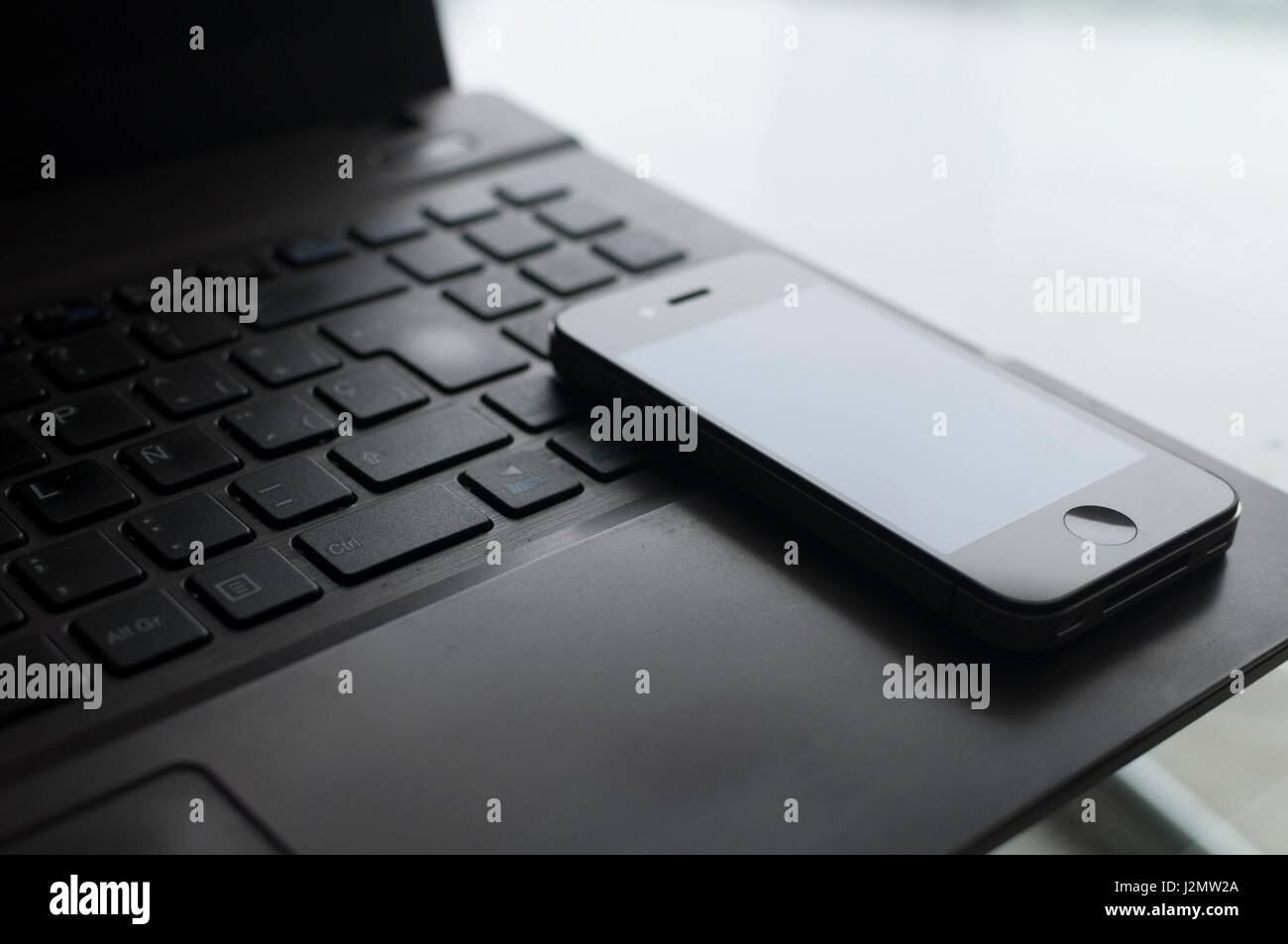 laptop with smart phone on glass table Stock Photo - Alamy
