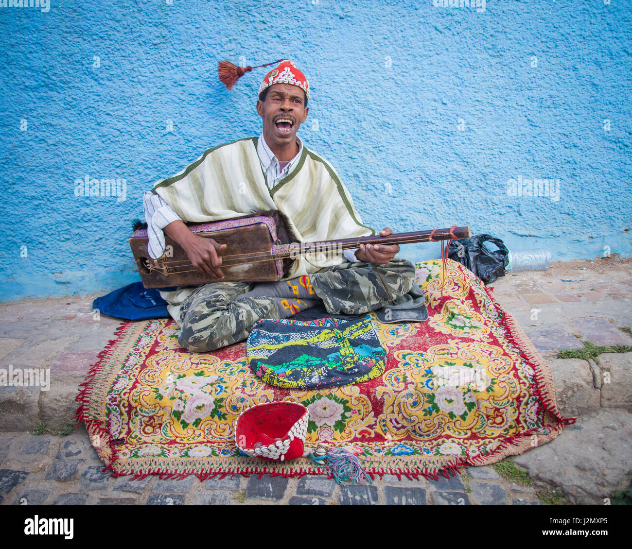 A street musician plays a sintir along a road in Chefchaouen, Morocco ...