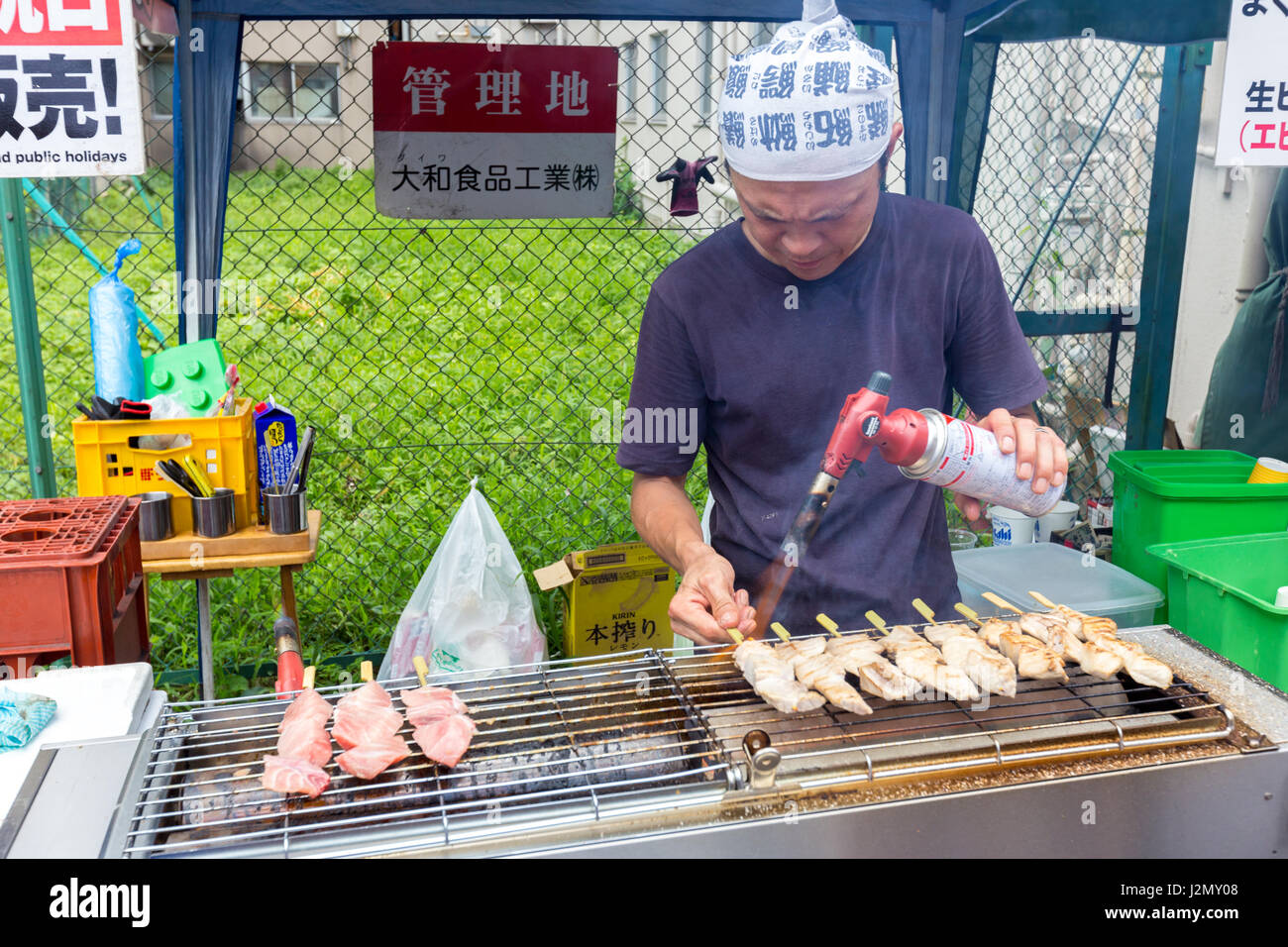 TOKYO, JAPAN - 18 JULY 2016 - Street vendor man cooks fish on sticks at ...