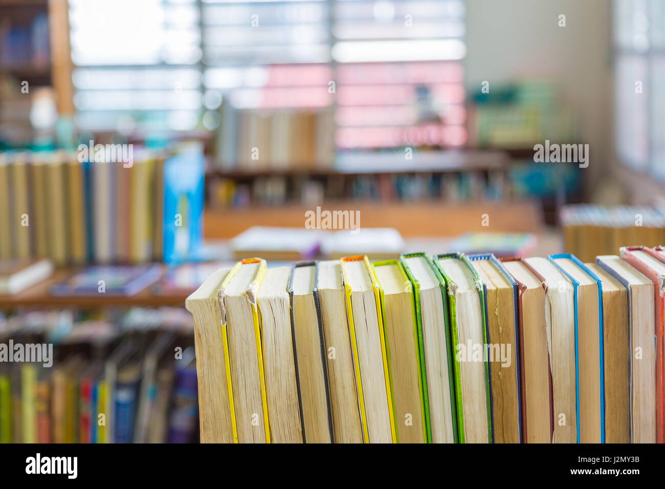 Hard covered library books line up on a shelf, selective focus with ...