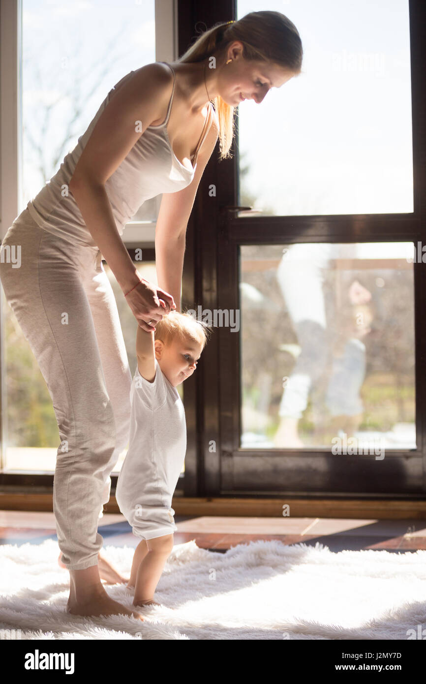 Baby girl making her first steps, learning to stand and walk through ...