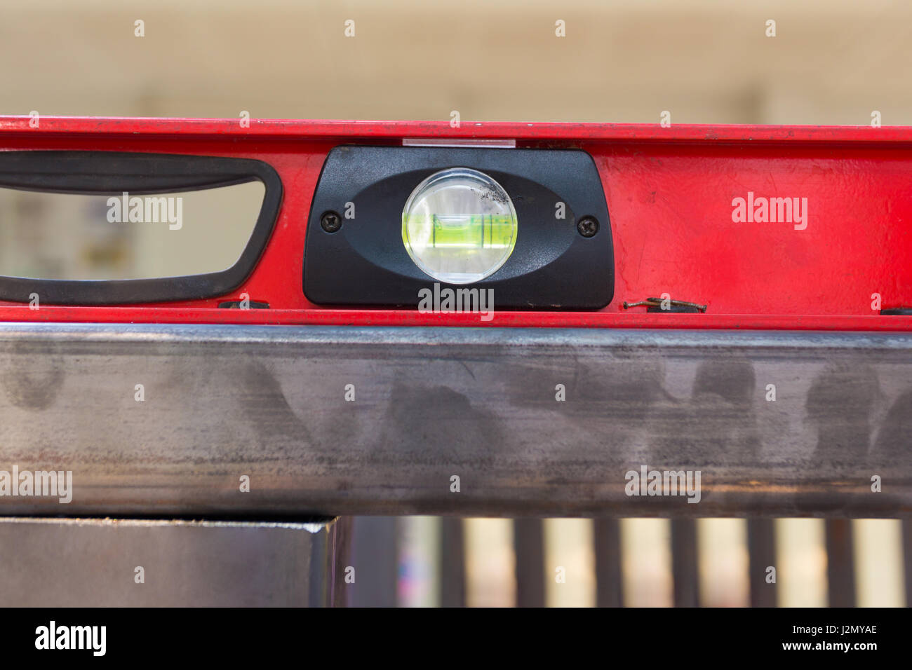 Close up of usded red construction level tool on steel beam, showing ...