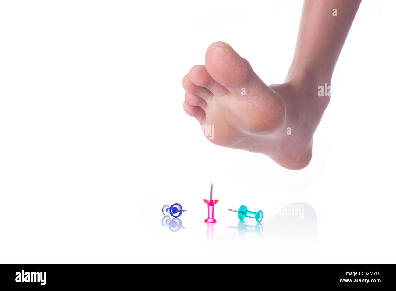 Person foot about to step on sharp push pins, on white background ...