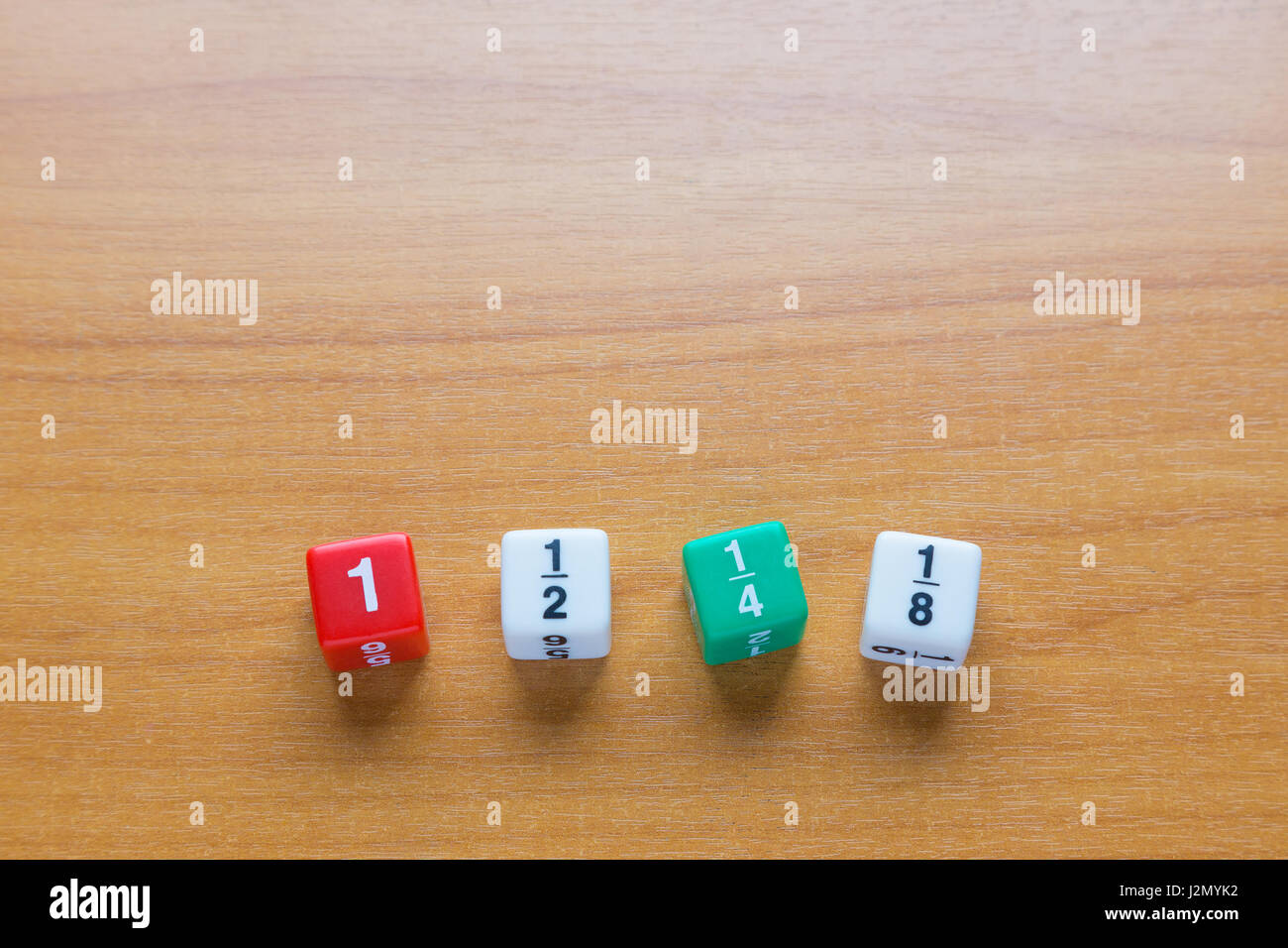 Four color fraction dices, 1, 1/2, 1/4, and 1/8, on wooden table ...
