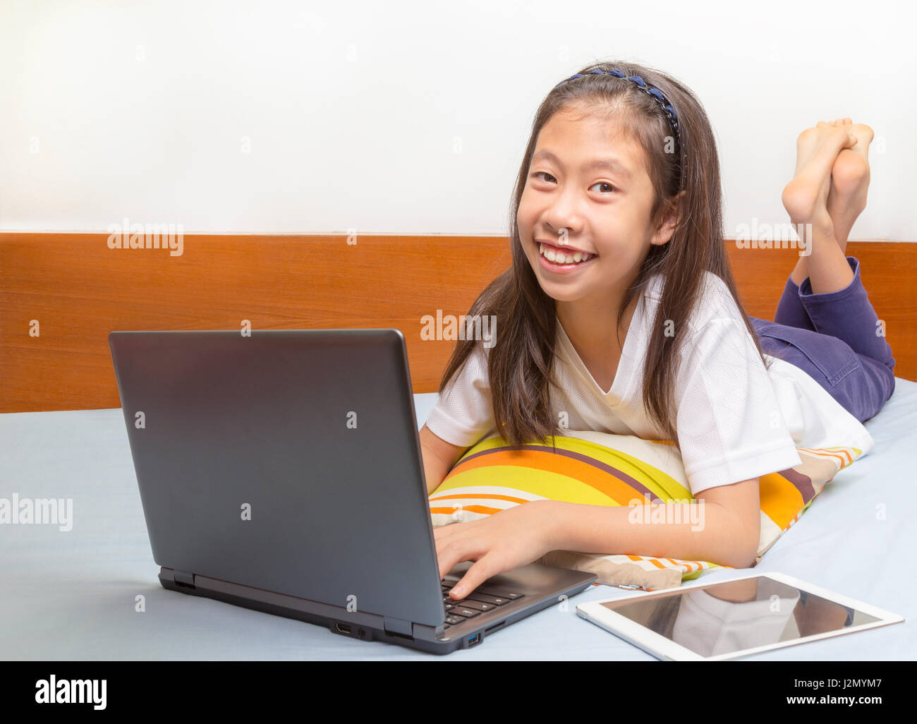Happy smiling asian girl using notebook computer and tablet computer on ...