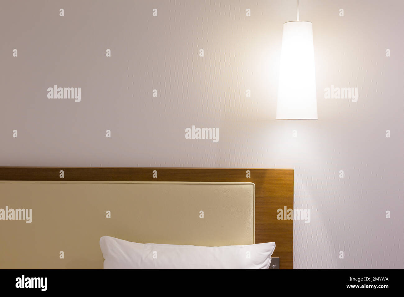Bed headboard, white pillow, and over head lamp, in simple and ...