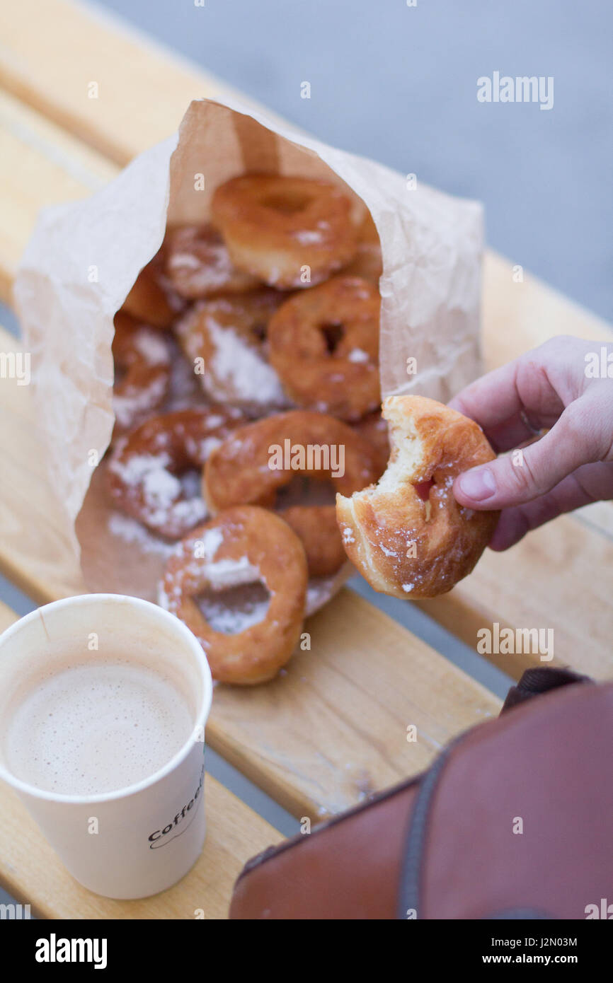 Fast food. Sugar donuts in the hands of the girl. Food on the street ...