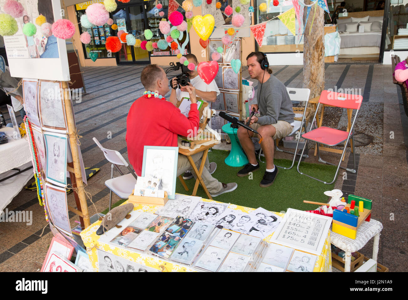 Caricature street artist having media interview at his stall in Manly ...