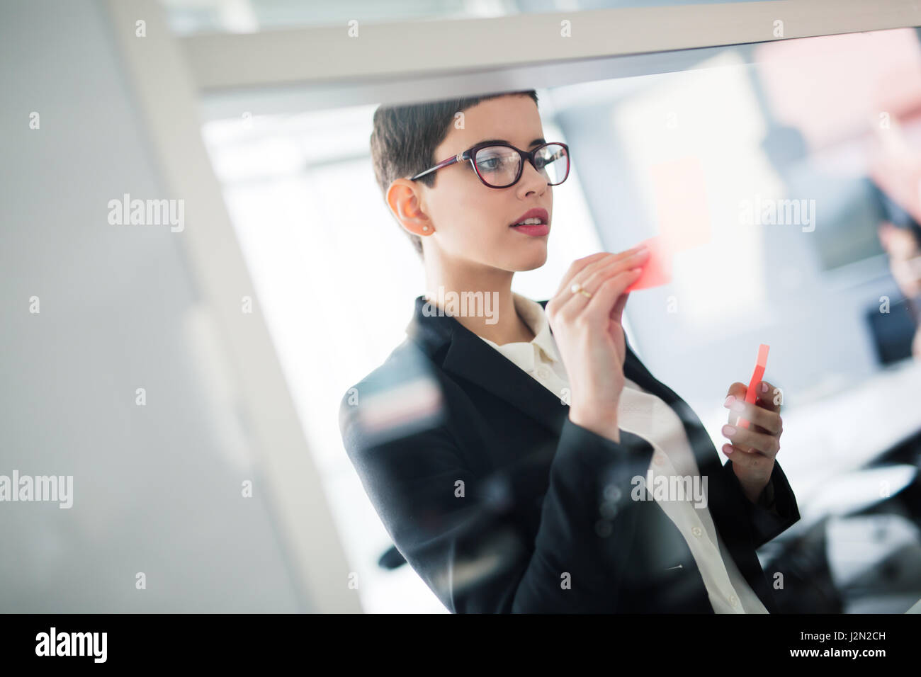 Beautiful businesswoman using sticky notes at office to plan project ...