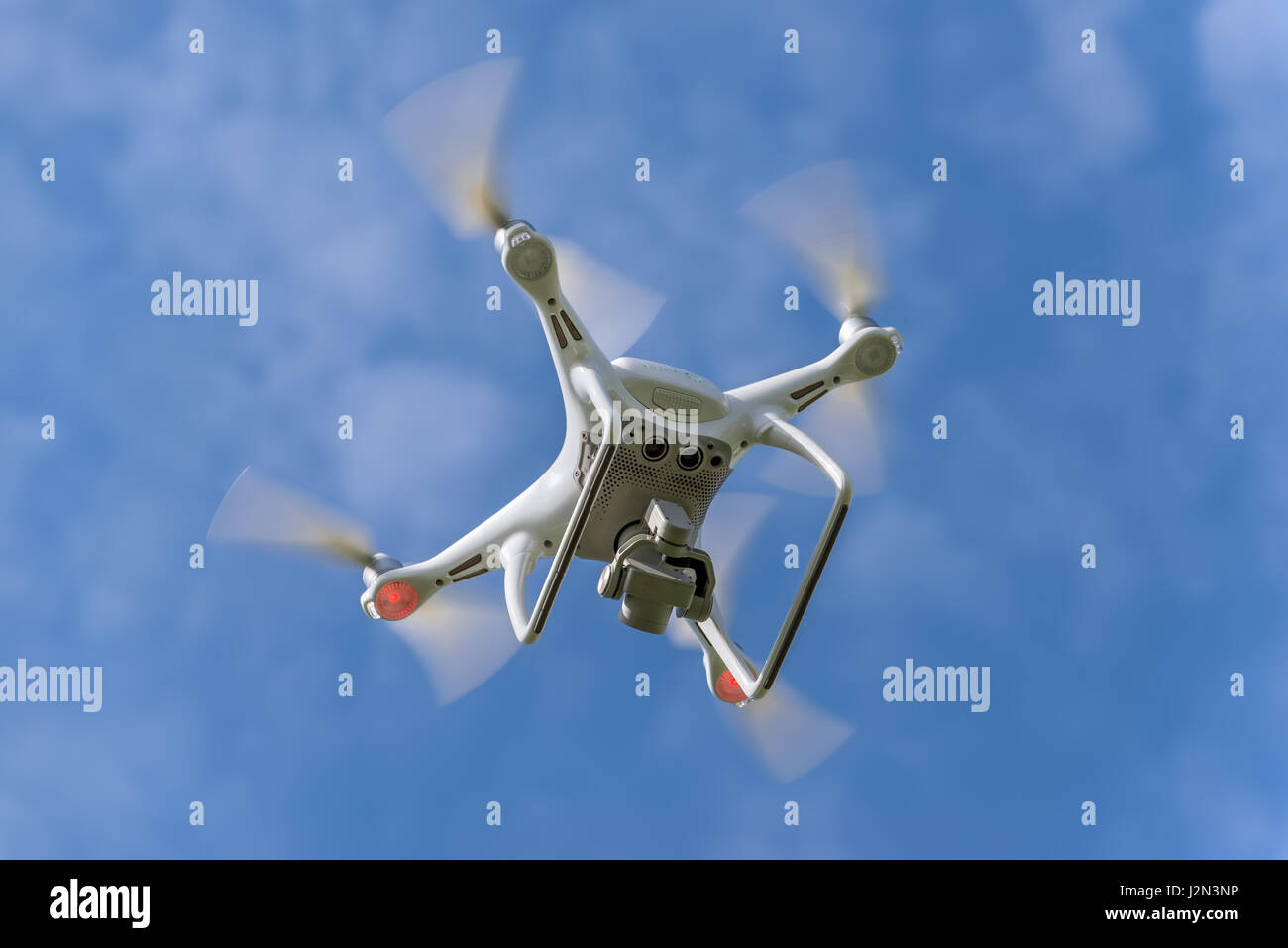 White drone hovering in a bright blue sky Stock Photo - Alamy
