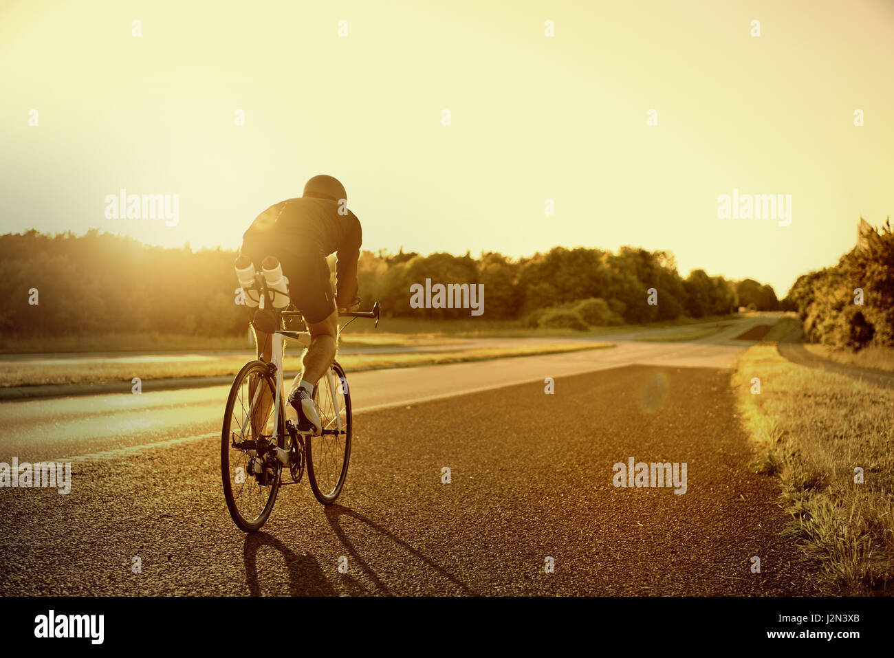 Back view of an athlete on a professional bicycle riding on empty ...
