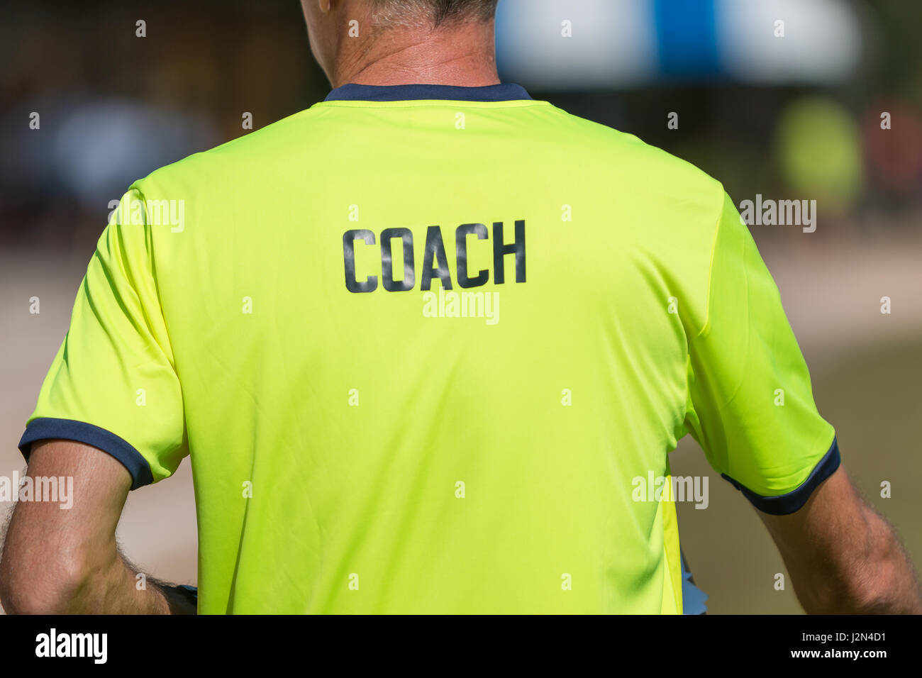 back of a coach's bright green color shirt with the word Coach written ...