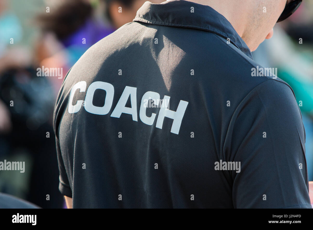 back of a coach's black shirt with the white word Coach written on it ...