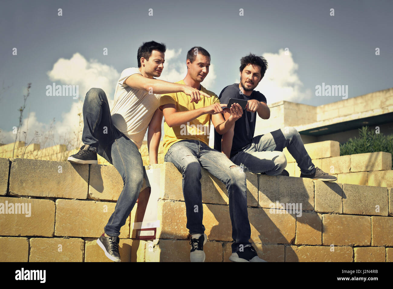 3 men sitting and talking outside Stock Photo - Alamy